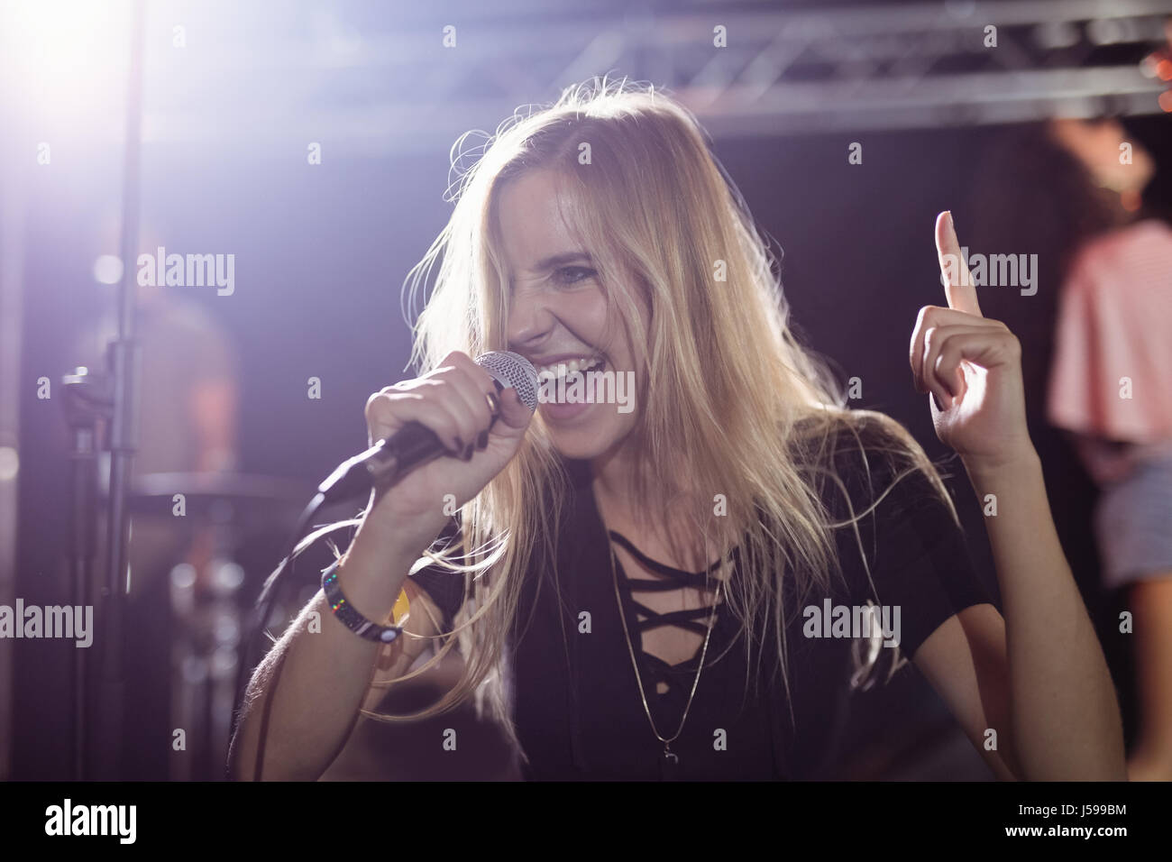 Happy young female singer performing at nightclub during music festival ...