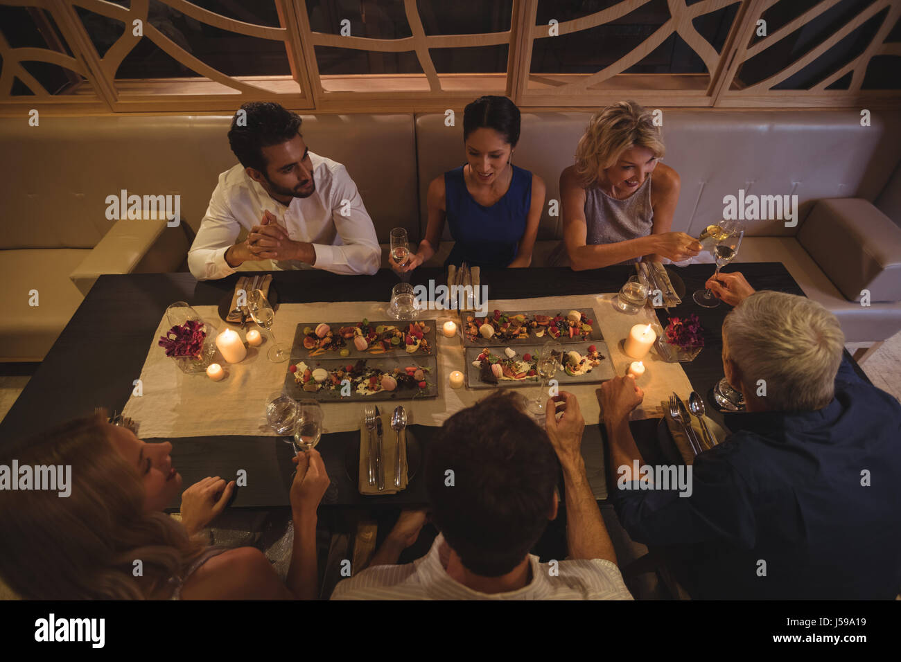 Happy friends interacting with each other while having dinner in ...