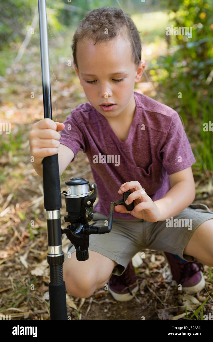 Boy adjusting the fishing rod in the forest Stock Photo - Alamy