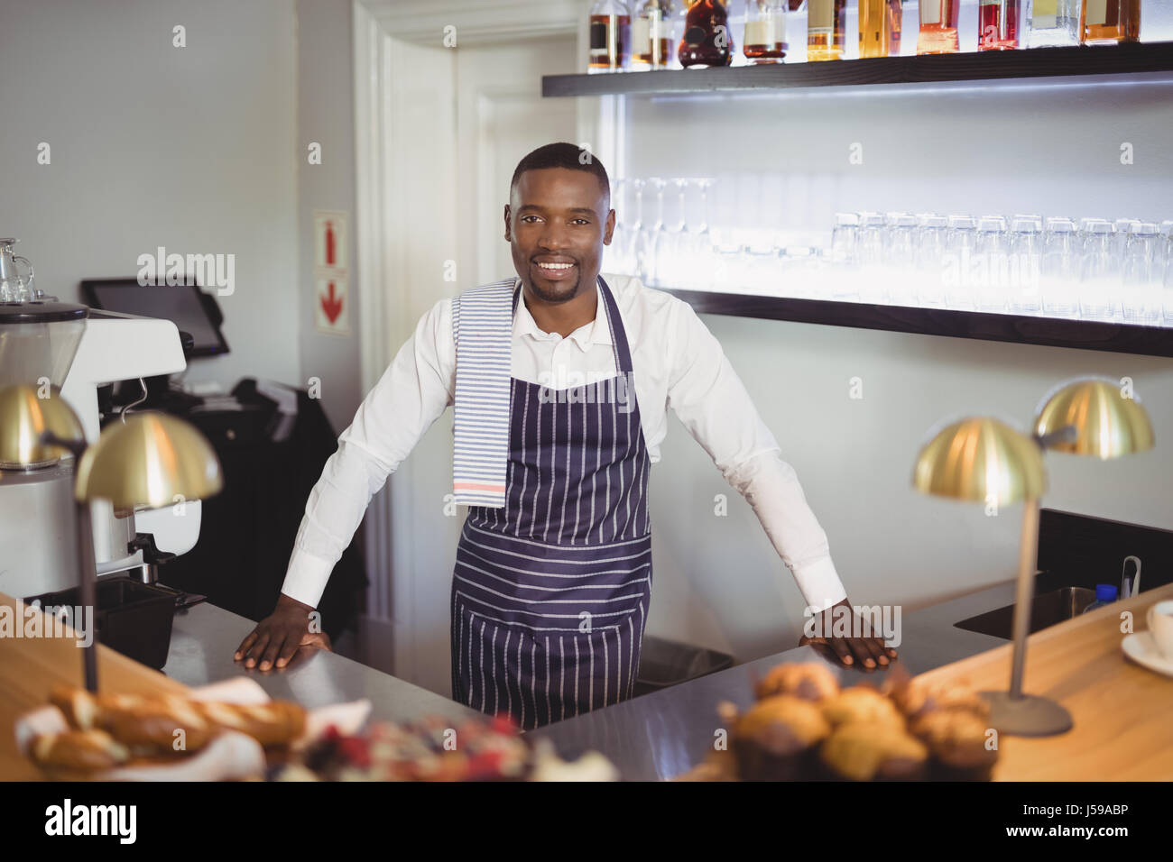 Portrait of smiling waiter standing at counter in restaurant Stock ...
