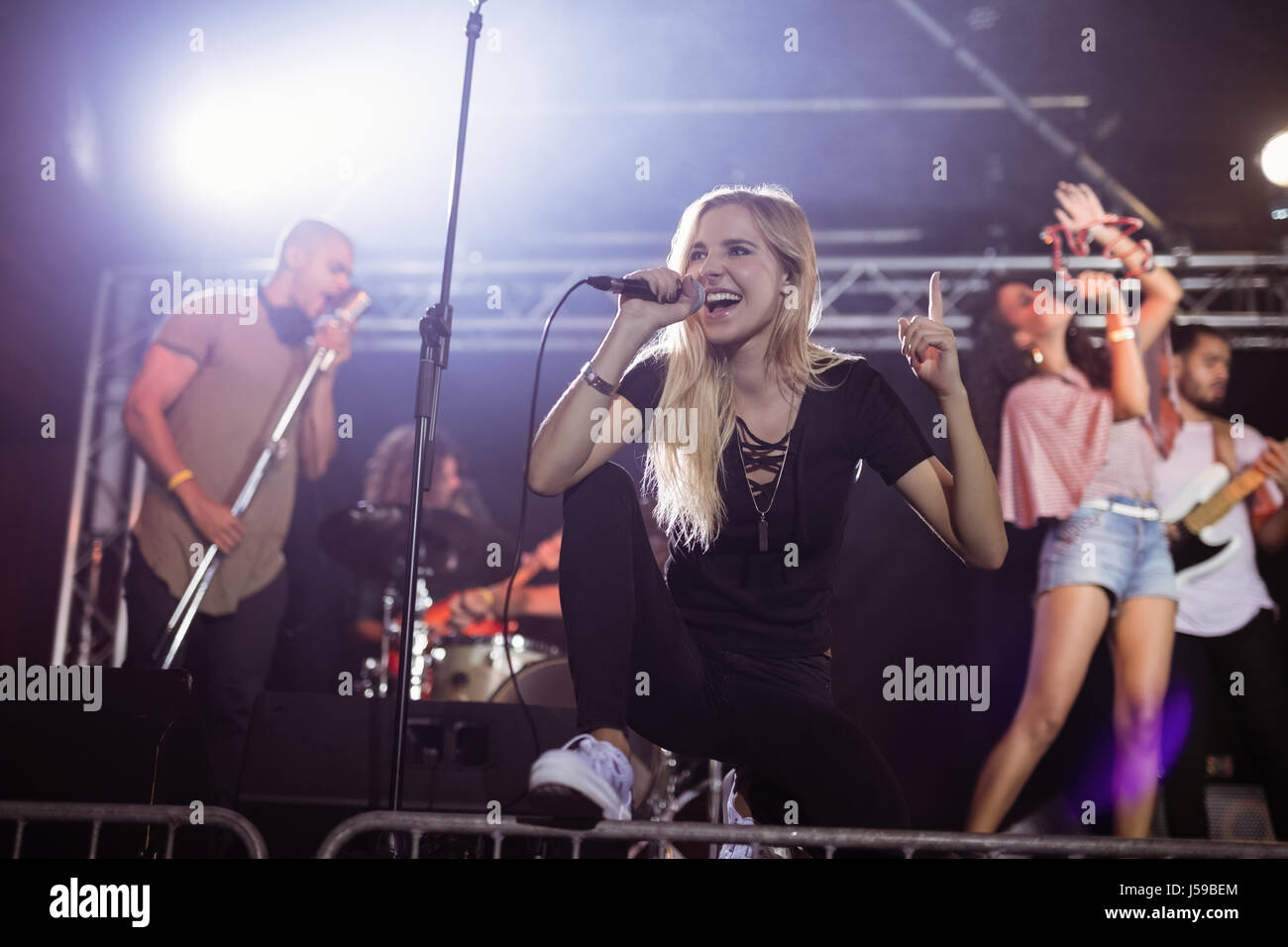 Young female singer performing with musicians at nightclub during music ...