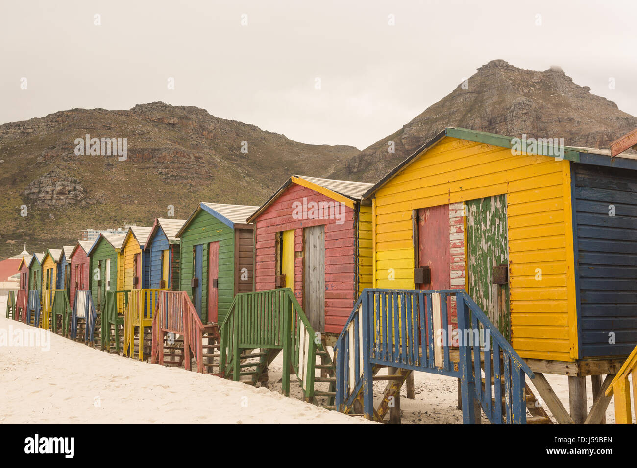 Multi colored wooden beach huts on sand against mountain Stock Photo ...