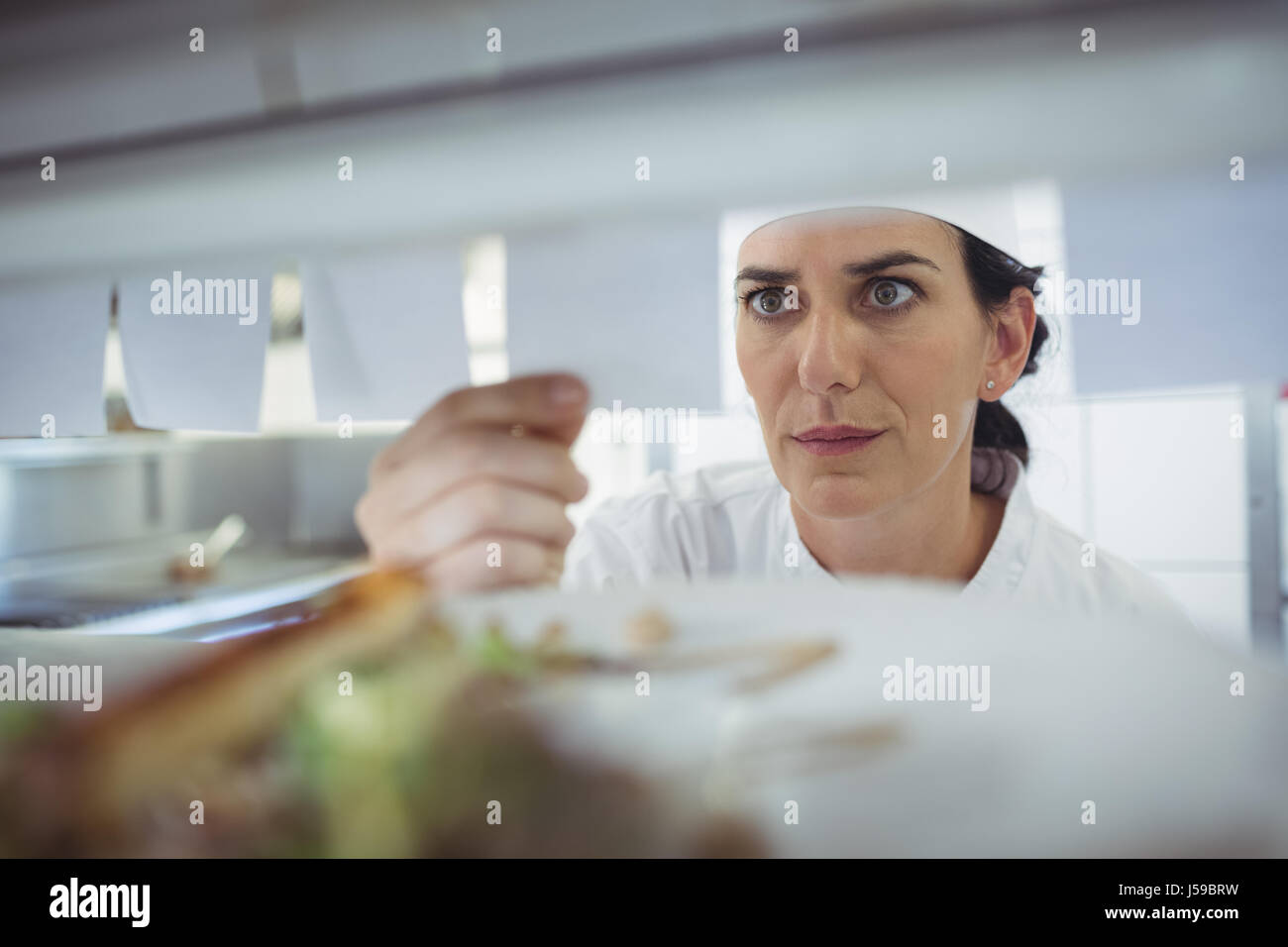 Female chef looking at an order list in the commercial kitchen at ...