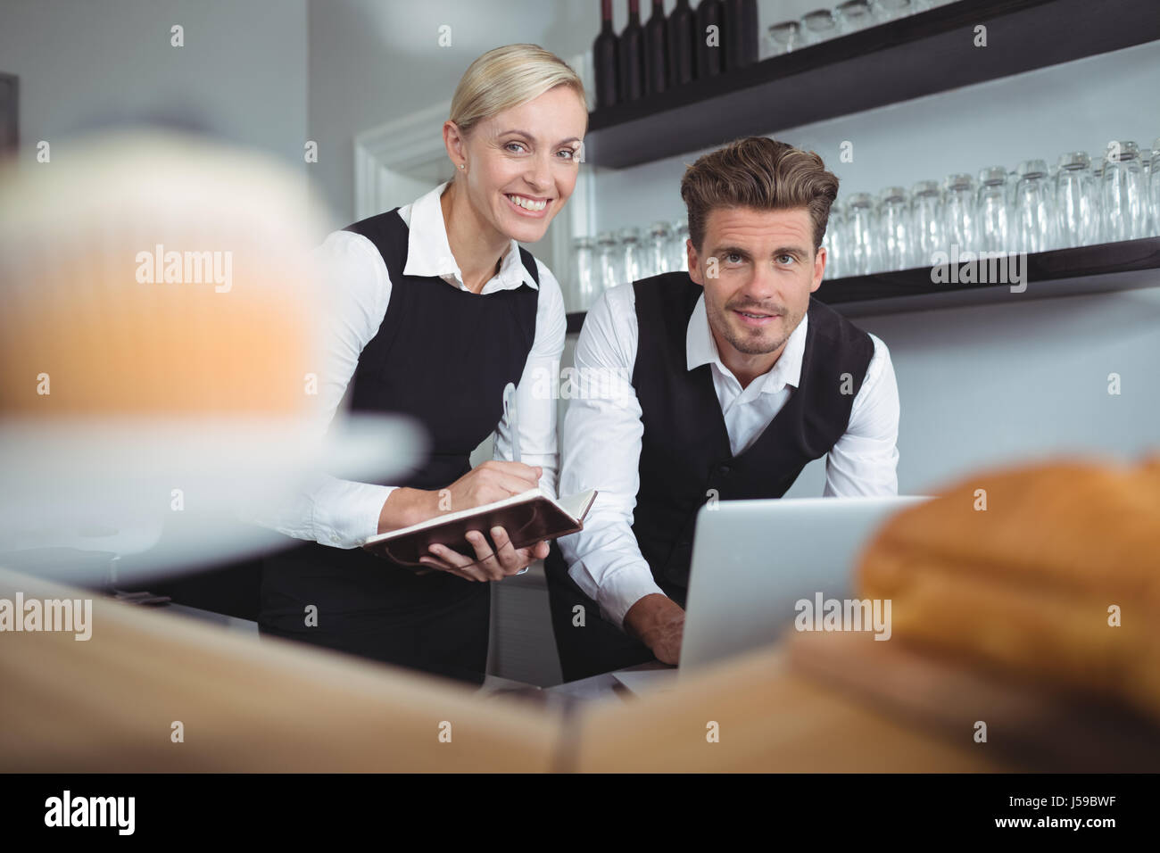 Portrait of smiling waiters using laptop at counter in restaurant Stock ...