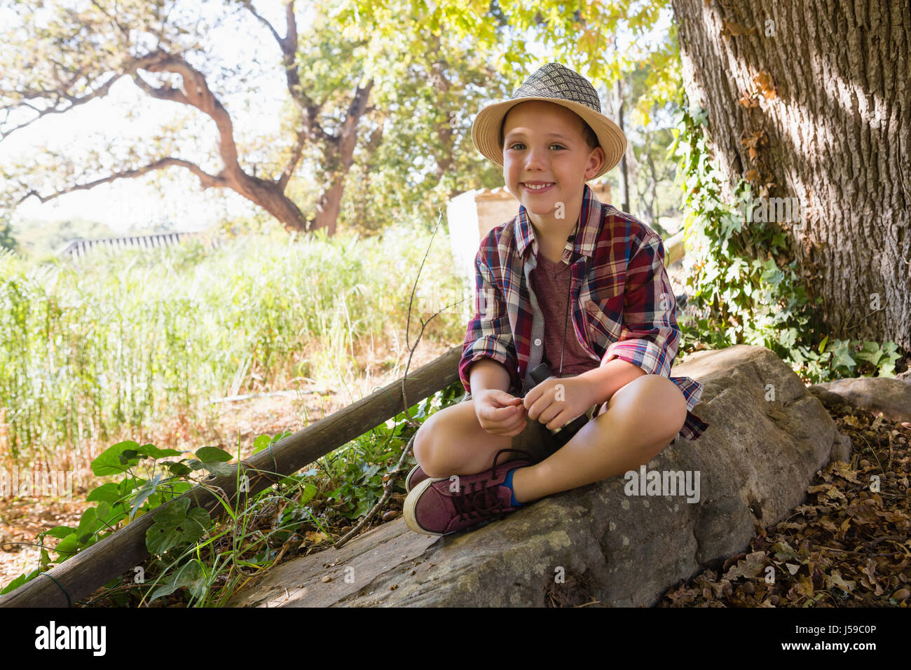 Portrait of smiling boy sitting on the rock in the forest Stock Photo ...