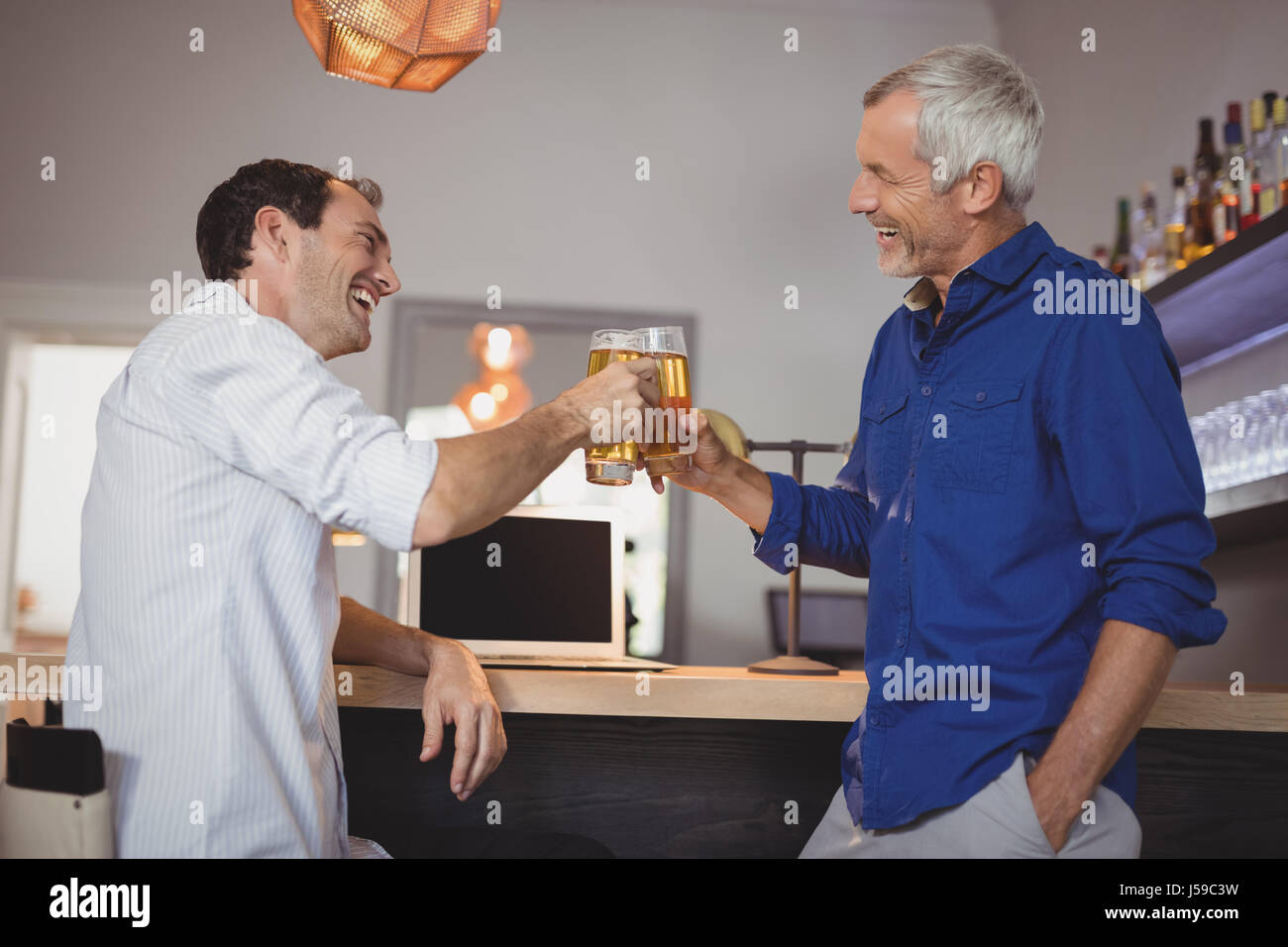 Two men toasting their beer glasses in restaurant Stock Photo - Alamy
