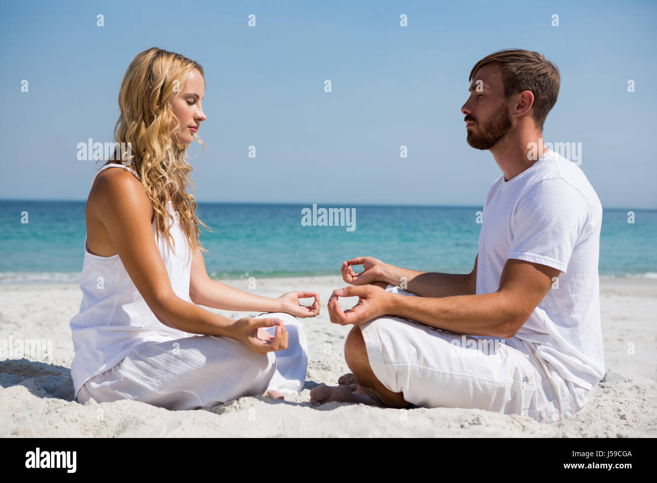 Side view of couple practicing meditation while sitting face to face at ...