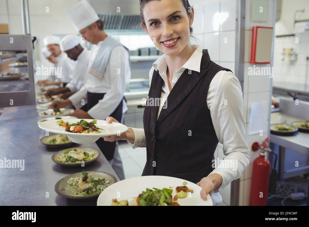 Waitress showing dishes to the camera and team of chefs working in ...