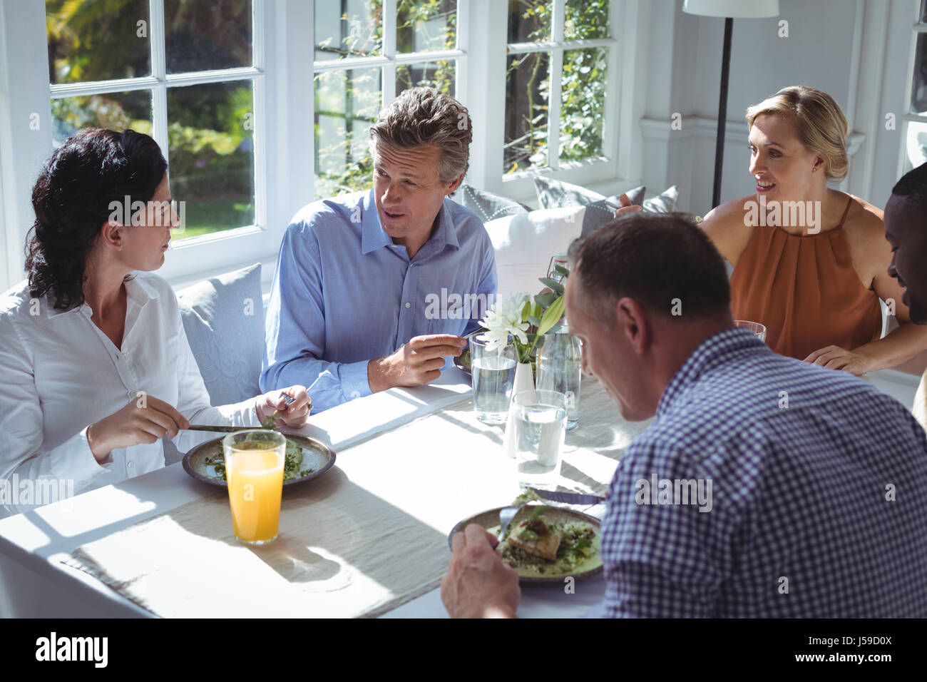Group of friends interacting while having meal in restaurant Stock ...