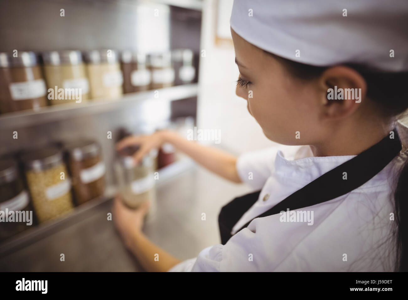 Female chef selecting a spice jar in the commercial kitchen at ...