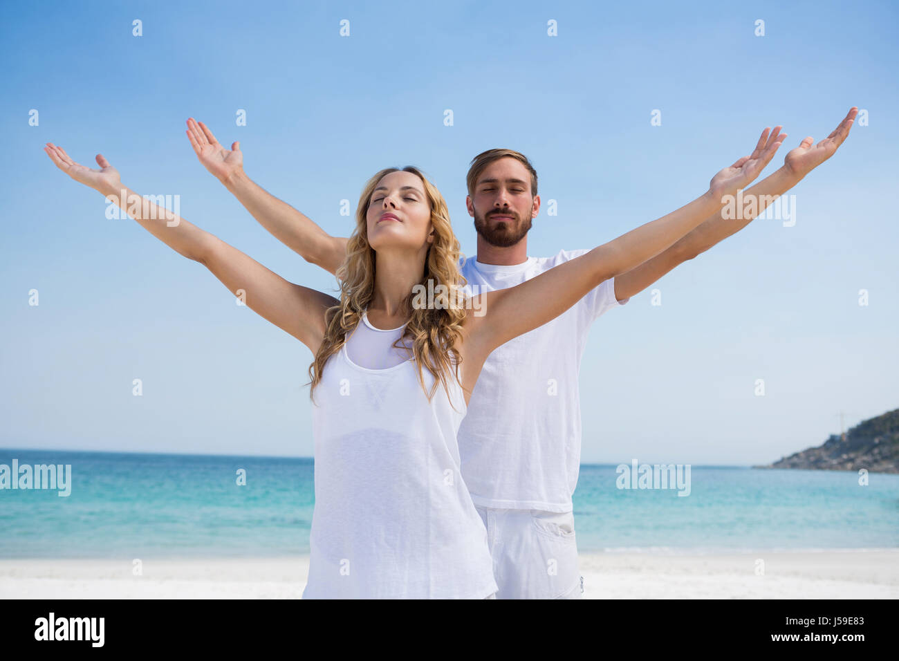Couple with arms outstretched exercising while standing at beach Stock ...
