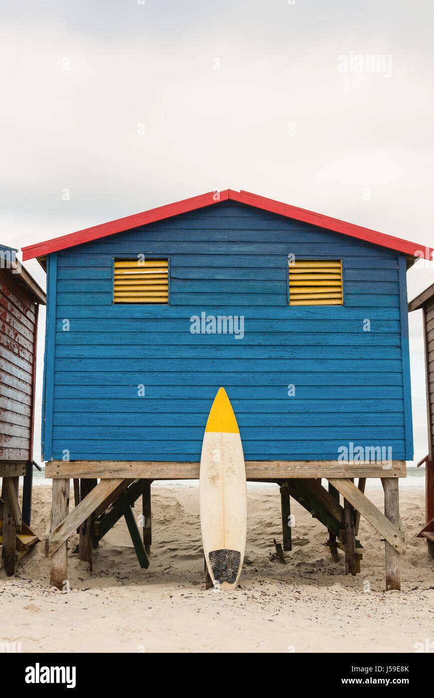 Surfboard by blue wooden hut on sand at beach Stock Photo - Alamy