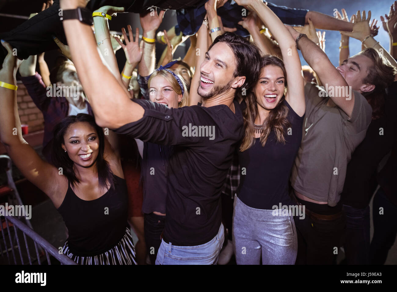 Cheerful crowd lifting performer at nightclub during music concert ...