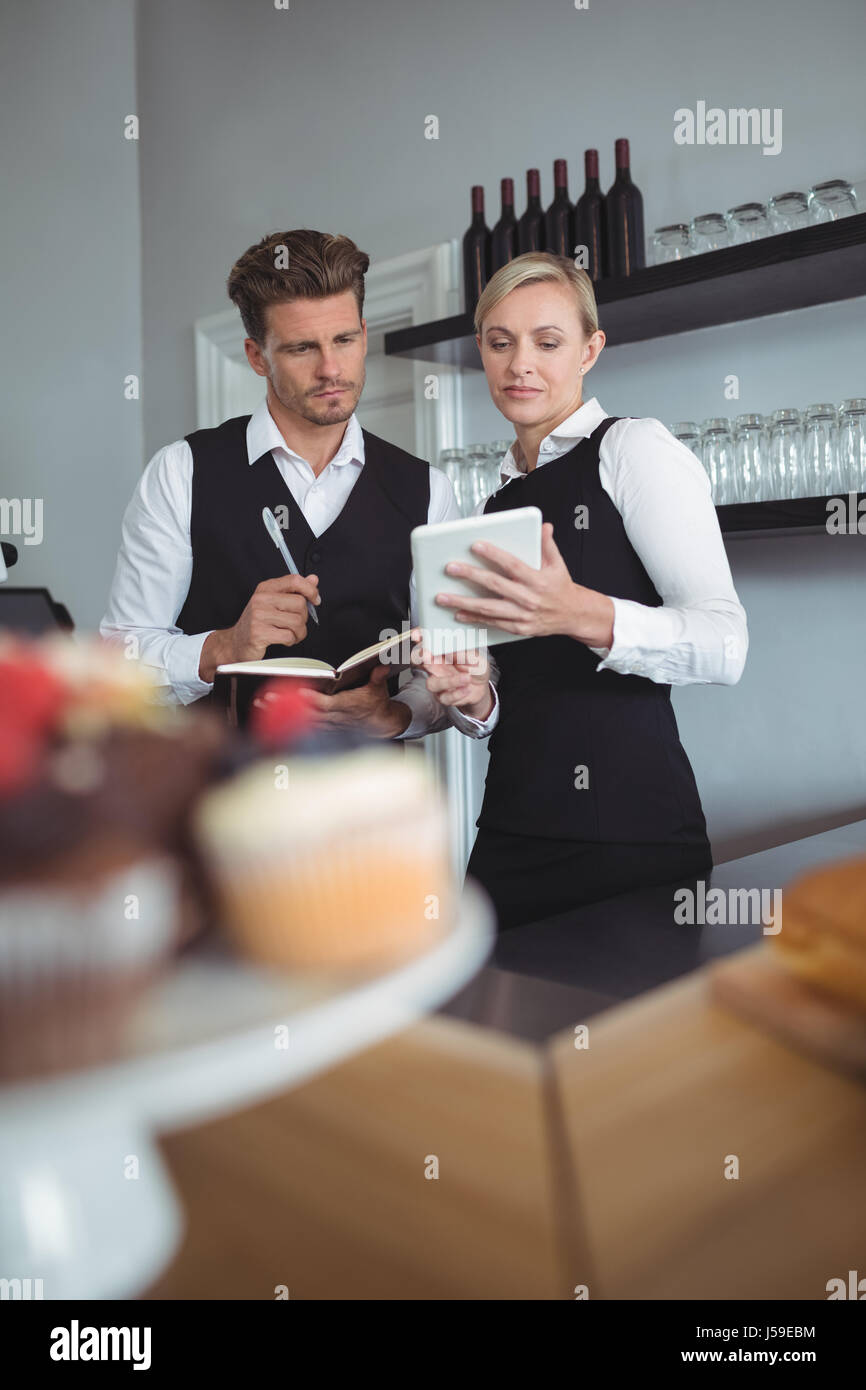 Waiters using digital tablet at counter in restaurant Stock Photo - Alamy