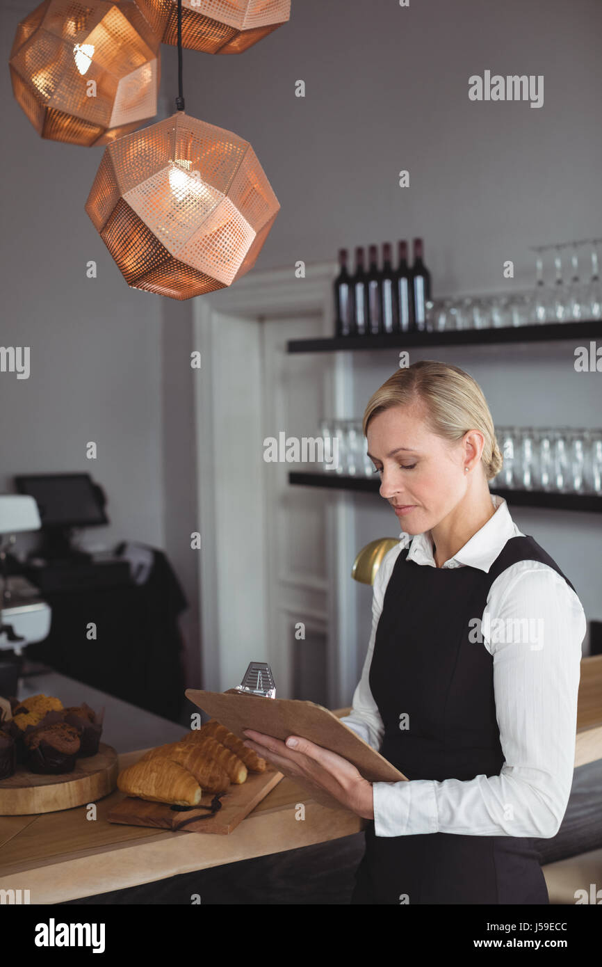 Waitress writing on notepad at counter in restaurant Stock Photo - Alamy