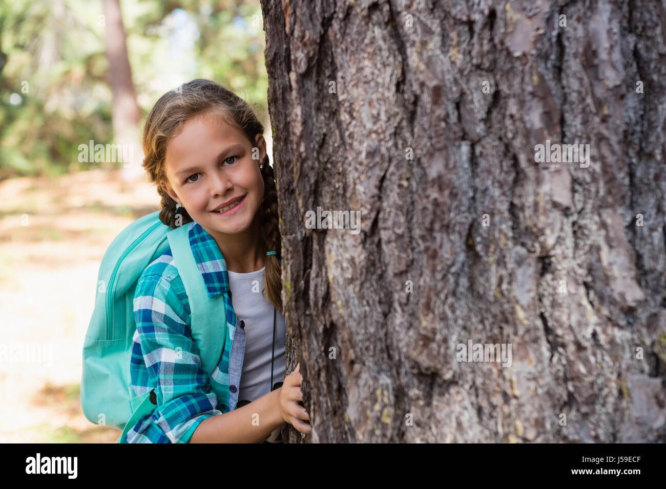 Portrait of smiling girl hiding behind the tree Stock Photo - Alamy