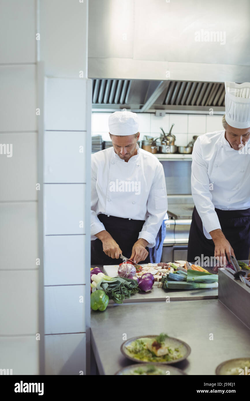 Chefs chopping vegetables on chopping board in the commercial kitchen ...