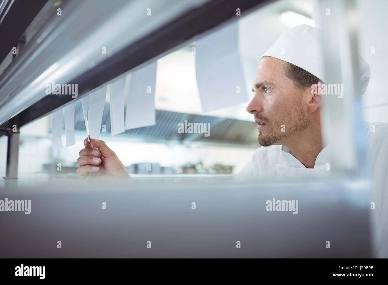Chef looking at an order list in the commercial kitchen at restaurant ...