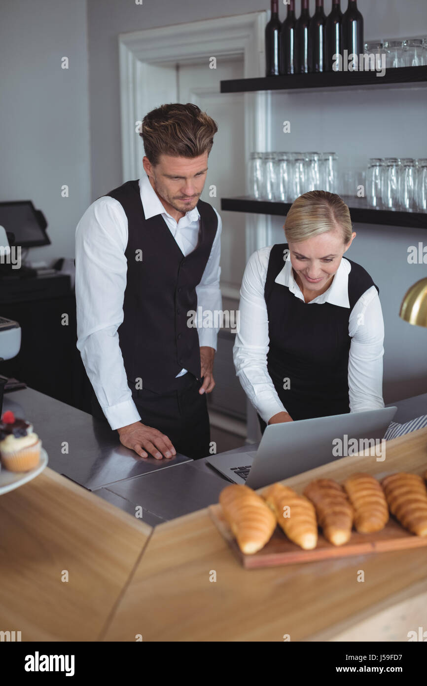 Waiter and waitress using laptop at counter in restaurant Stock Photo ...
