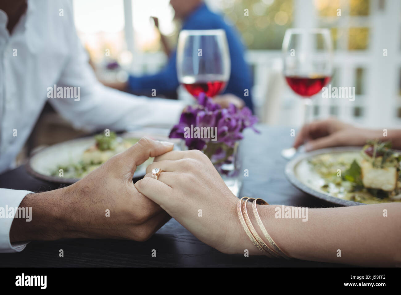 Couple holding hands while having meal in restaurant Stock Photo - Alamy