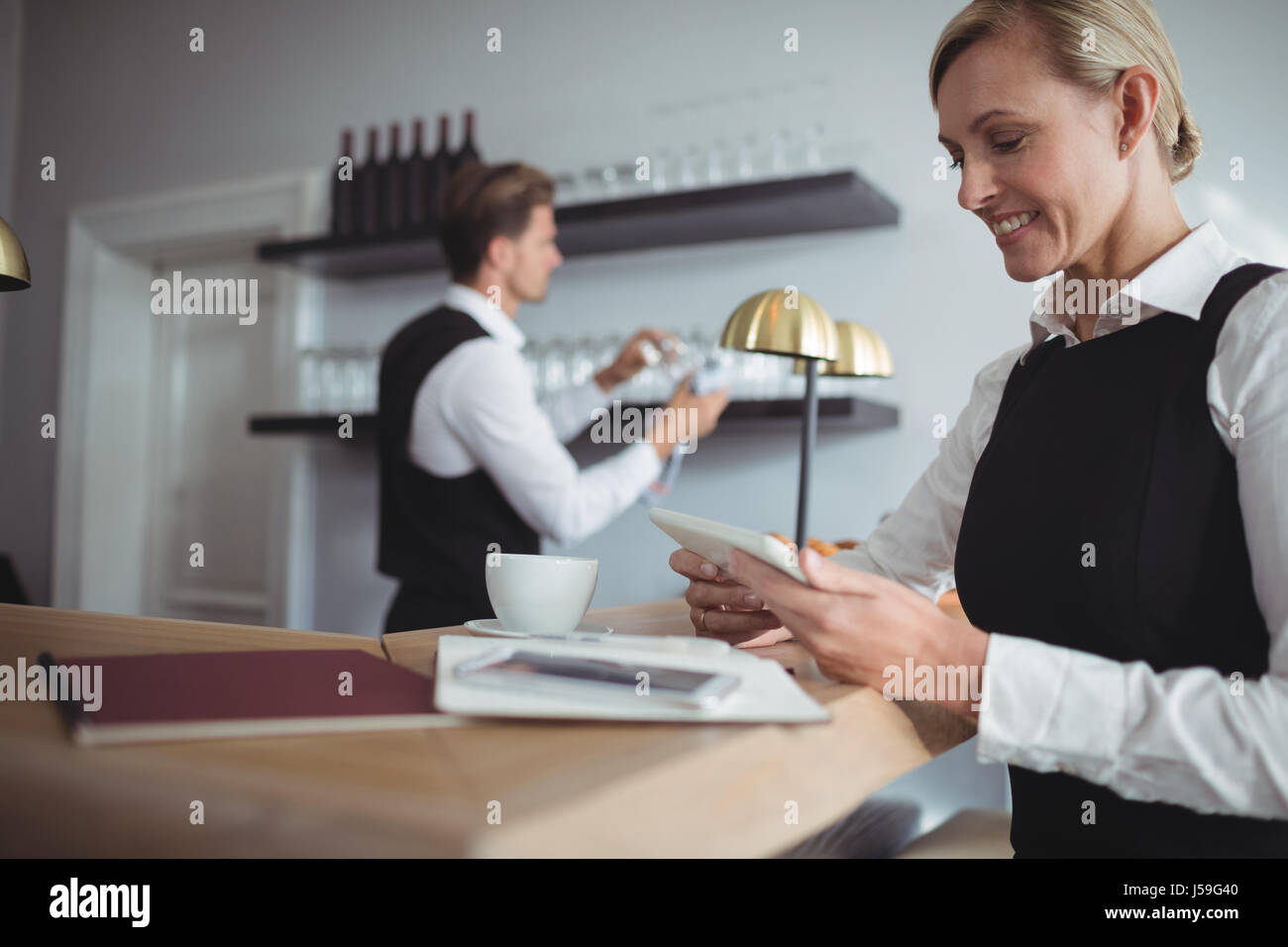 Smiling waitress using digital tablet at counter in a restaurant Stock ...
