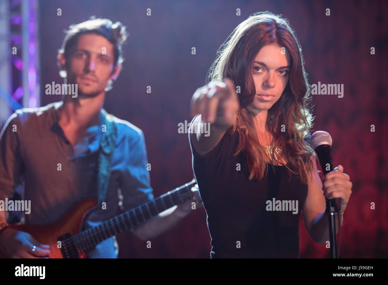 Portrait of female singer with male guitarist performing at nightclub ...