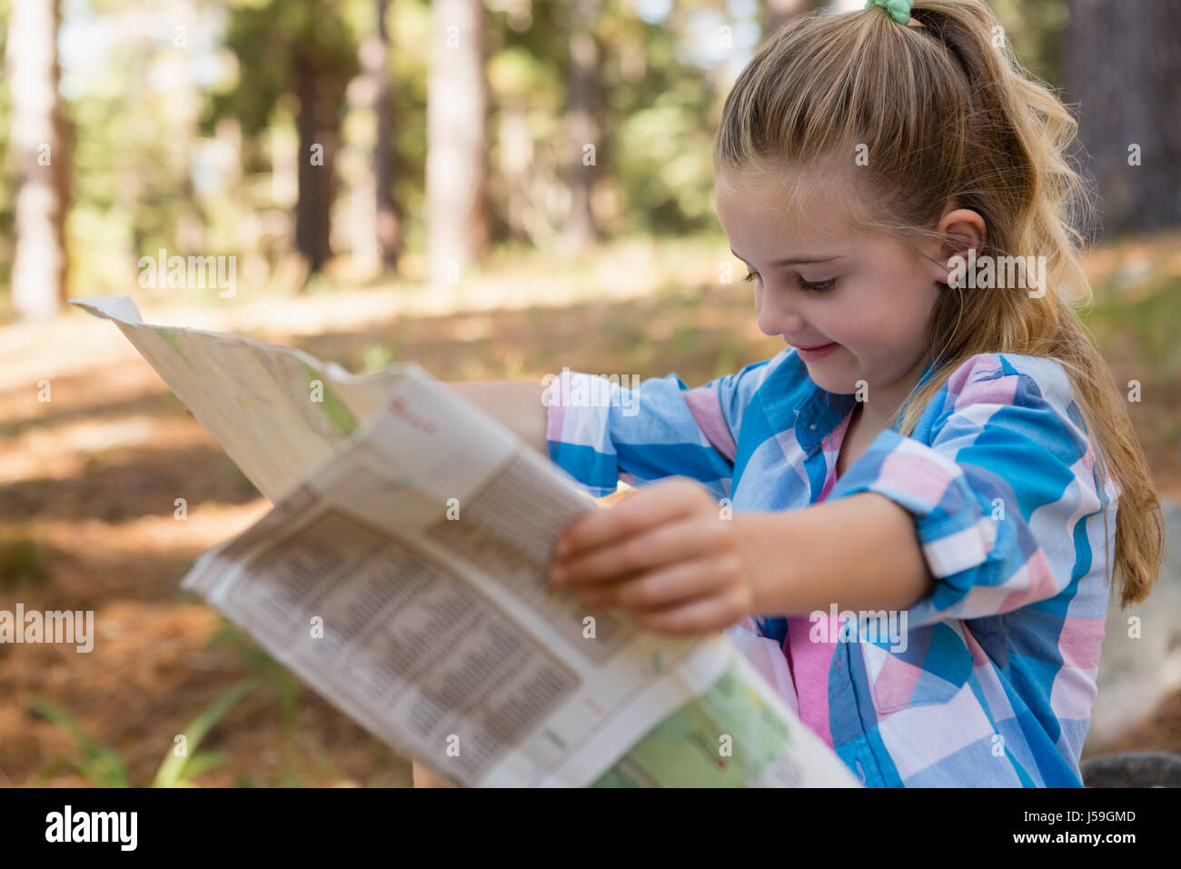 Smiling girl reading the map in the forest Stock Photo - Alamy