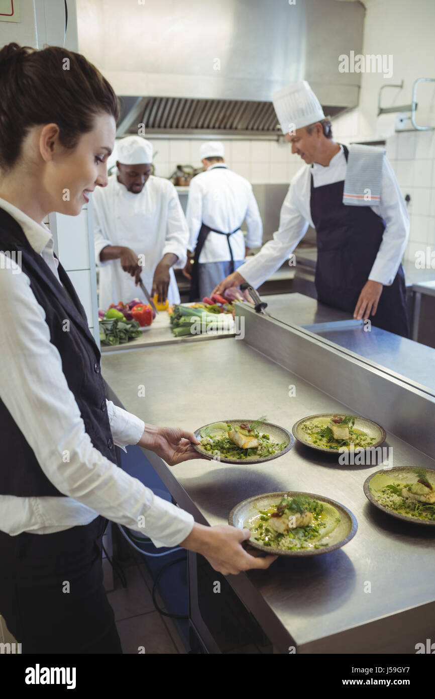 Waitress taking food dishes from order station in the commercial ...