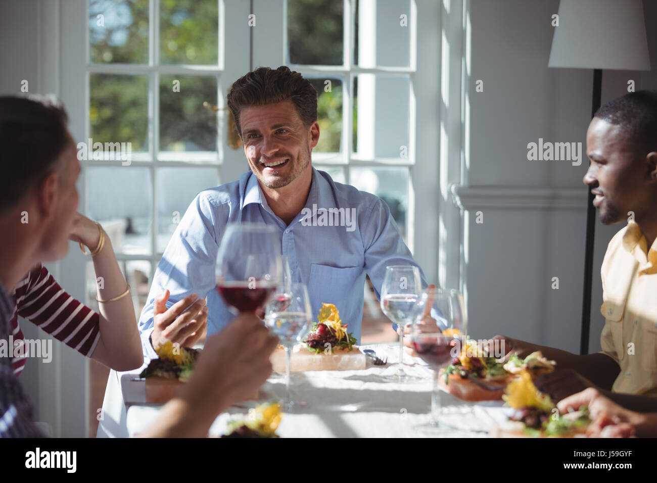 Group of friends interacting while having meal in restaurant Stock ...