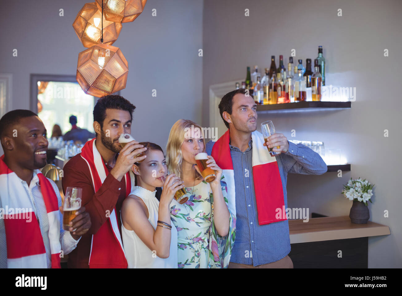 Group of friends drinking beer while watching match in bar restaurant ...