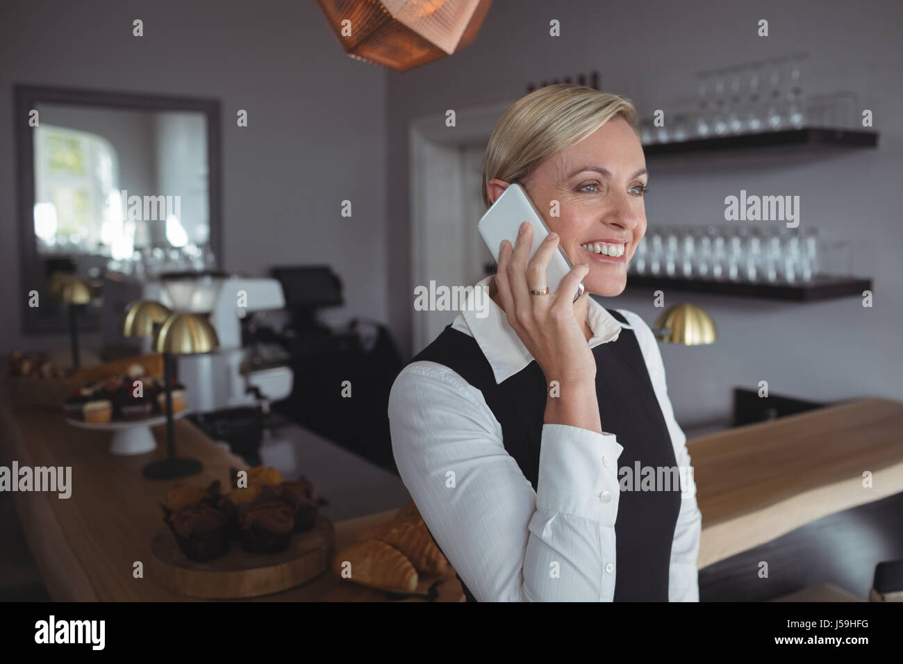 Smiling waitress talking on mobile phone in restaurant Stock Photo - Alamy