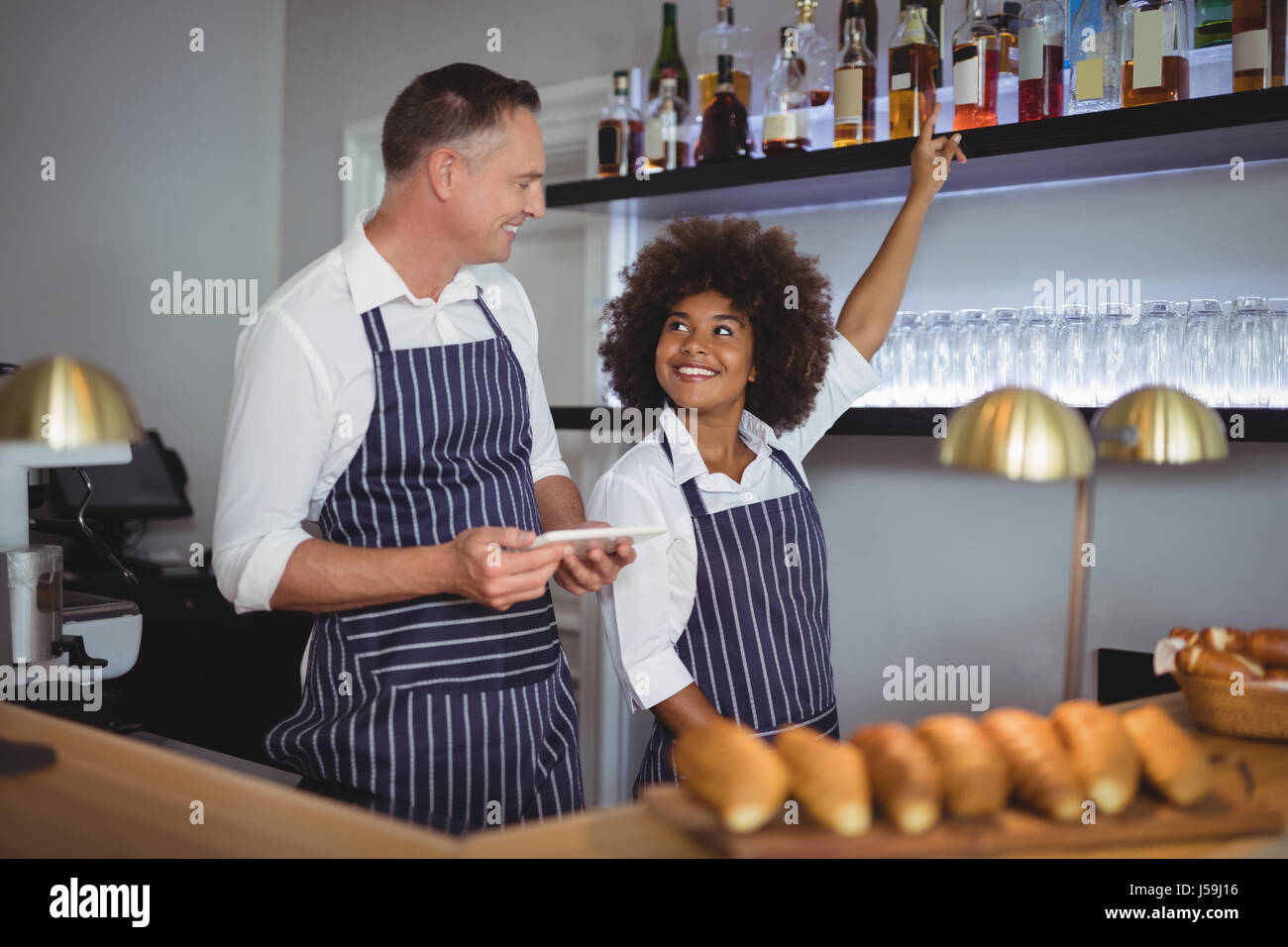 Waiter and waitress interacting with each other at counter in ...
