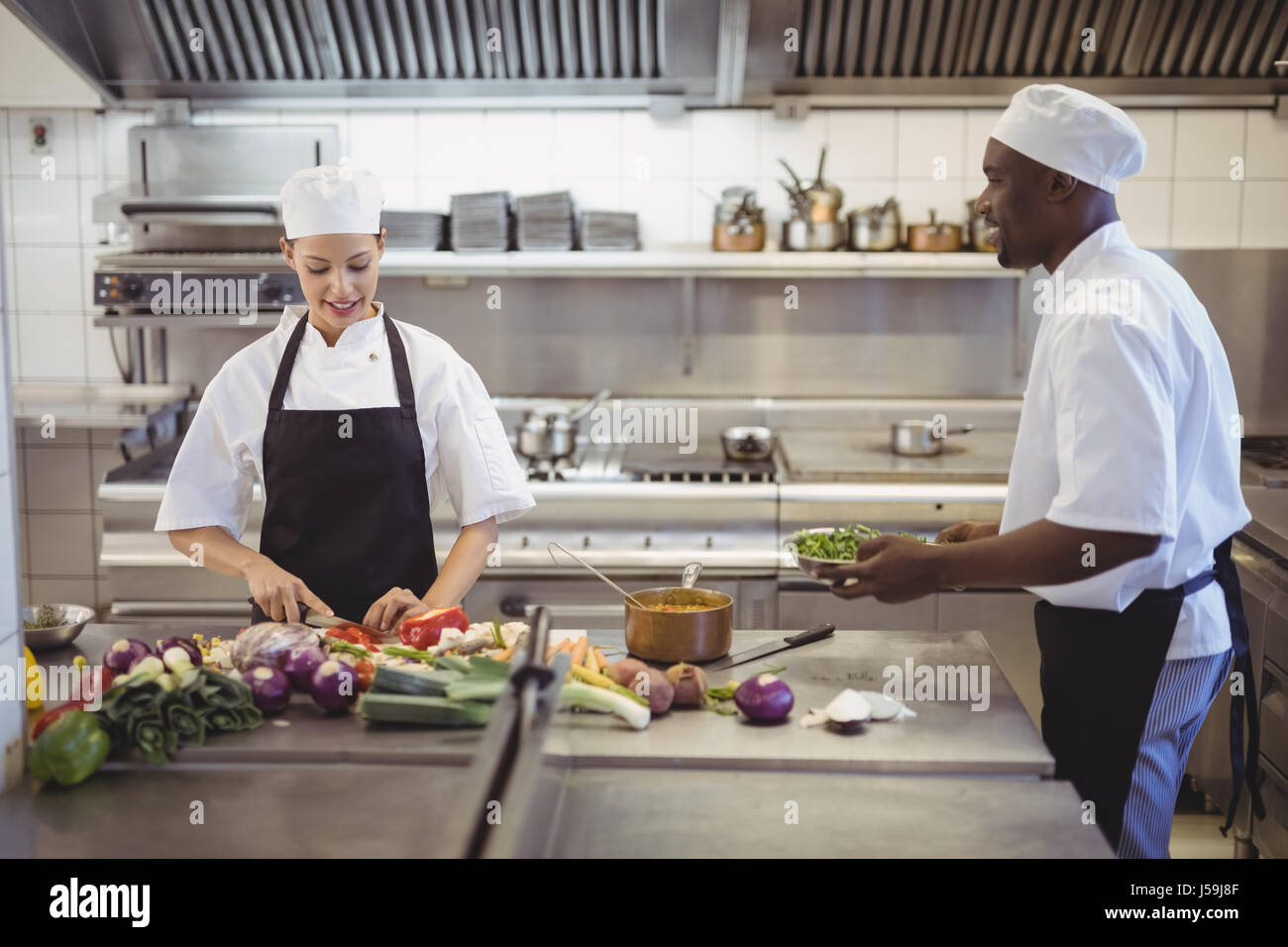 Chefs chopping vegetables on chopping board in the commercial kitchen ...