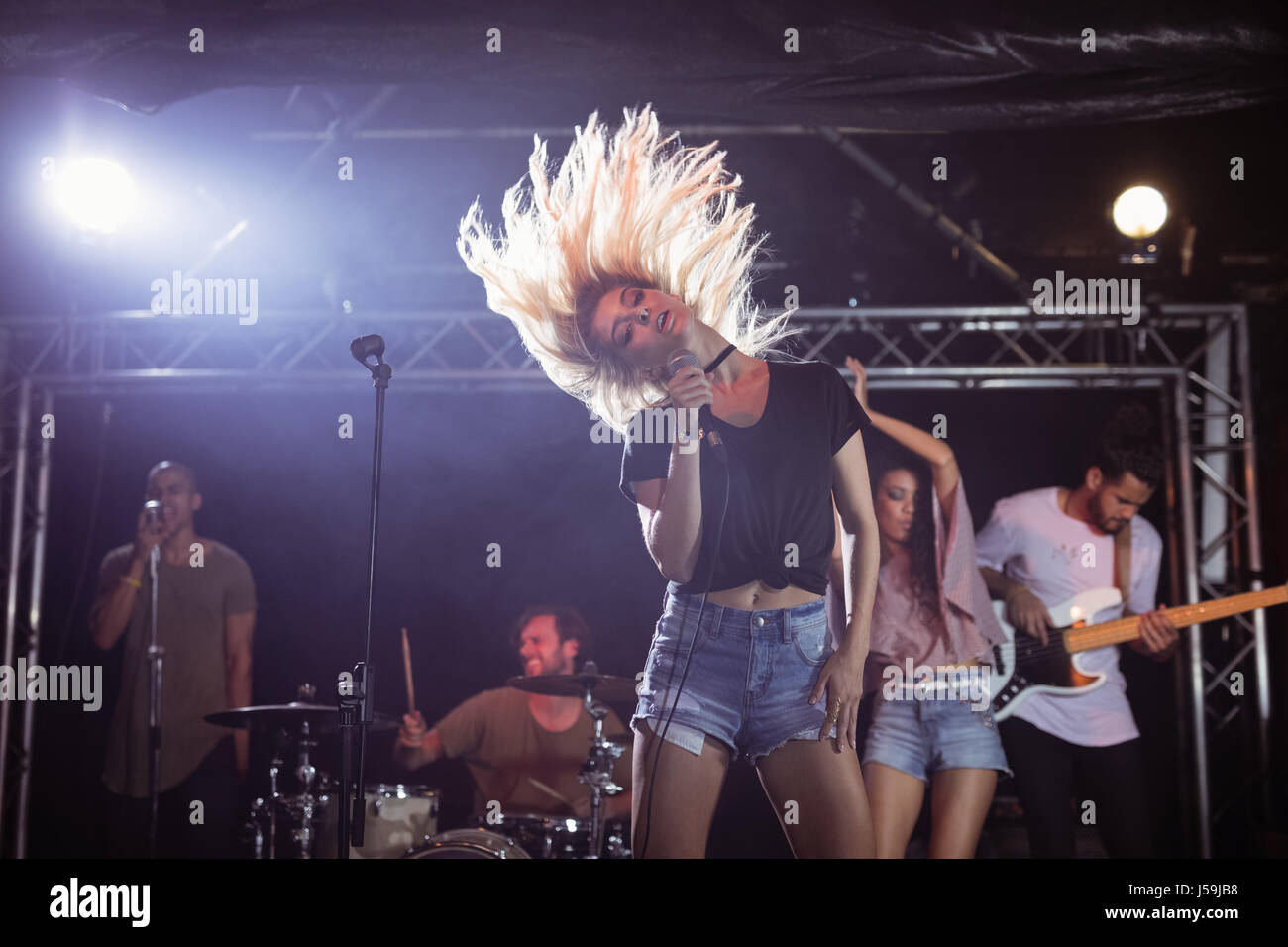 Young female singer with musicians performing during music festival at ...