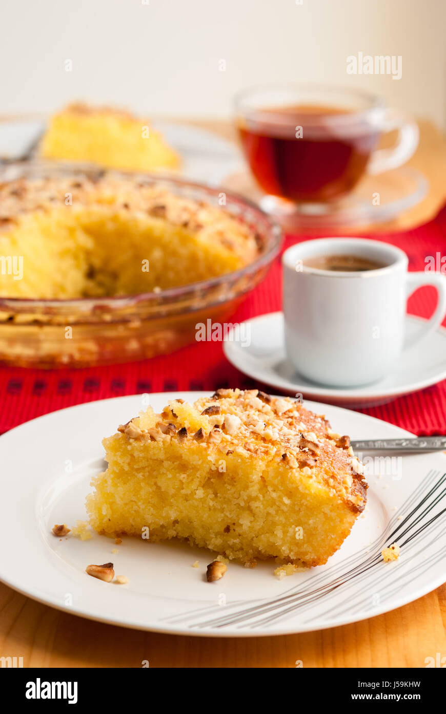 Shamali (semolina cake, basbousa) served on white plates with cup of ...
