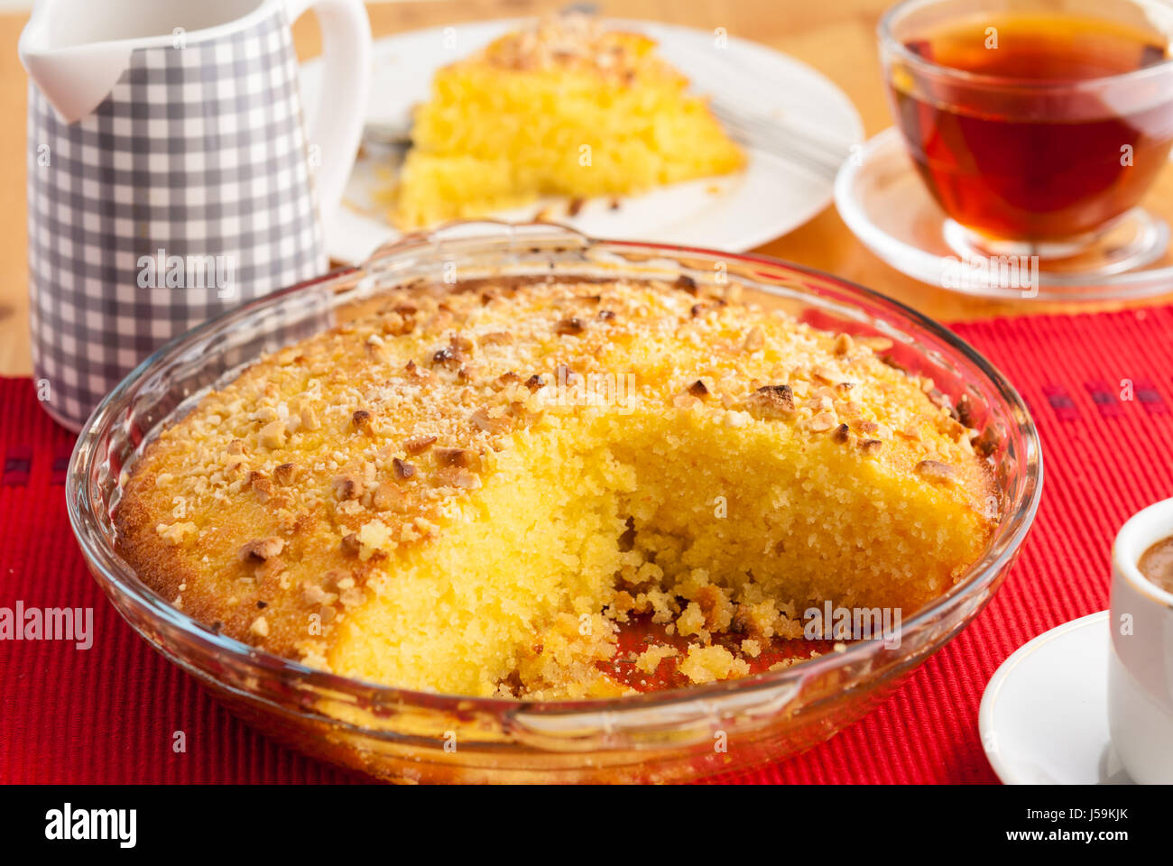 Shamali (semolina cake, basbousa) served on white plates with cup of ...