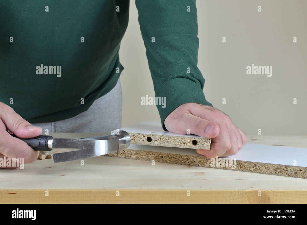 Hammering wooden dowels in to a particle board on working table Stock ...