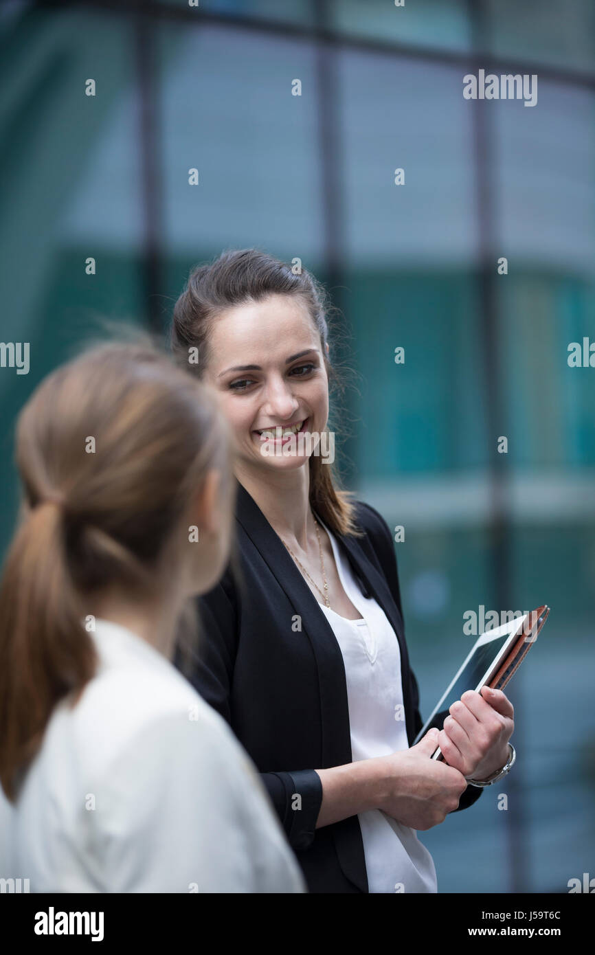 Portrait of two caucasian business women talking outside modern office ...