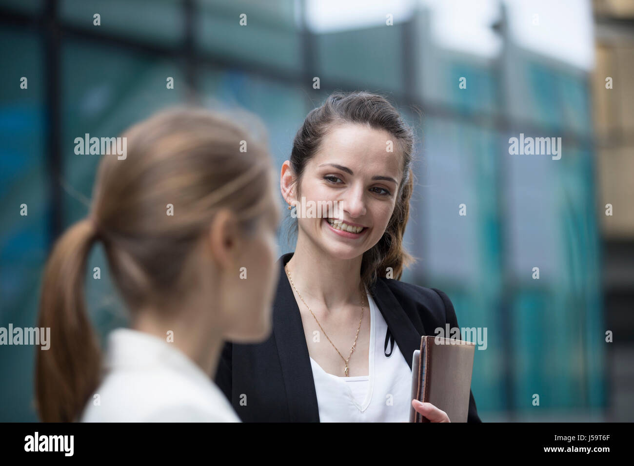 Portrait of two caucasian business women talking outside modern office ...