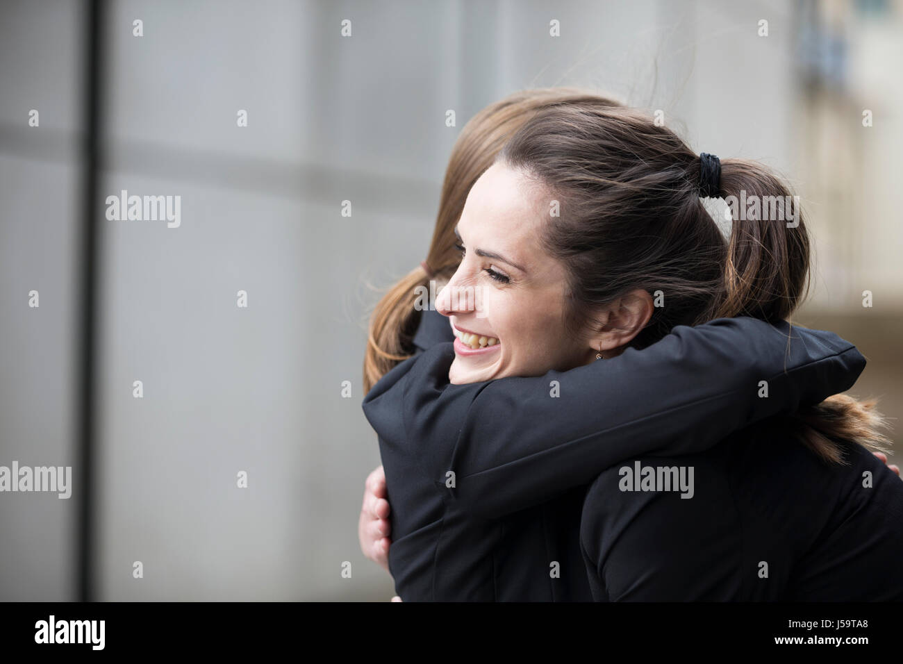 Two happy Businesswomen hugging each other outside office building ...