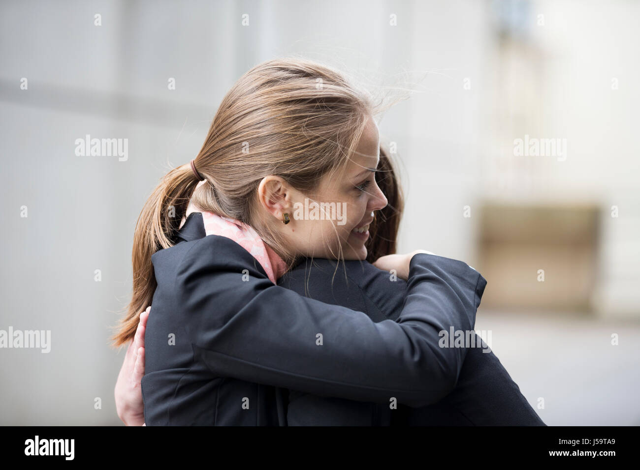 Two happy Businesswomen hugging each other outside office building ...