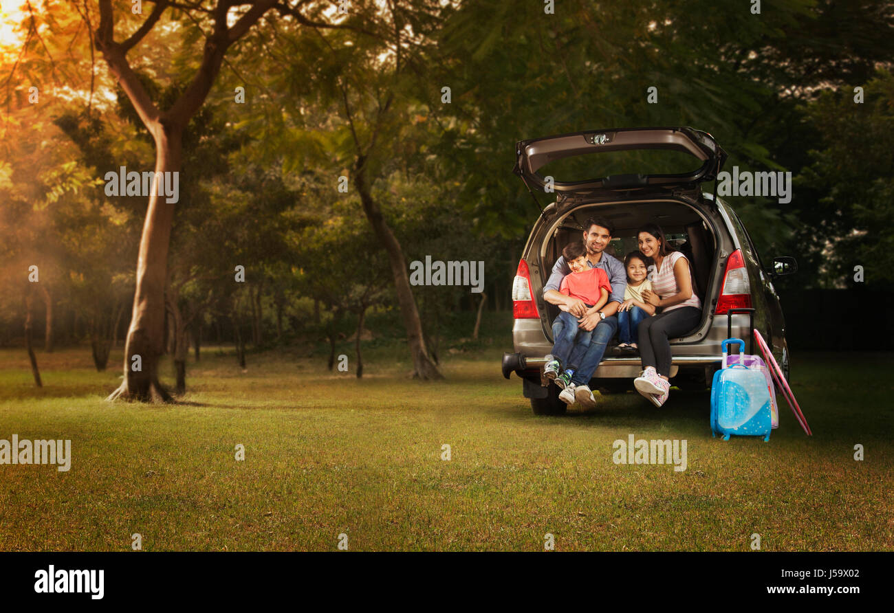 Family sitting together in back of car with open hatchback at picnic ...