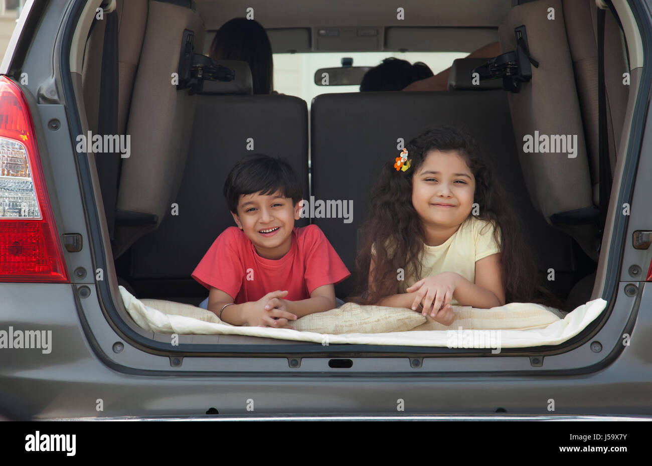 Brother and sister leaning in open boot of car Stock Photo - Alamy