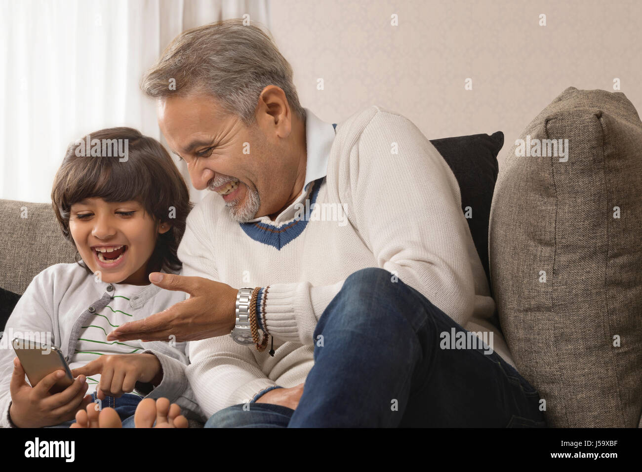 Smiling grandfather and grandson using mobile phone Stock Photo - Alamy