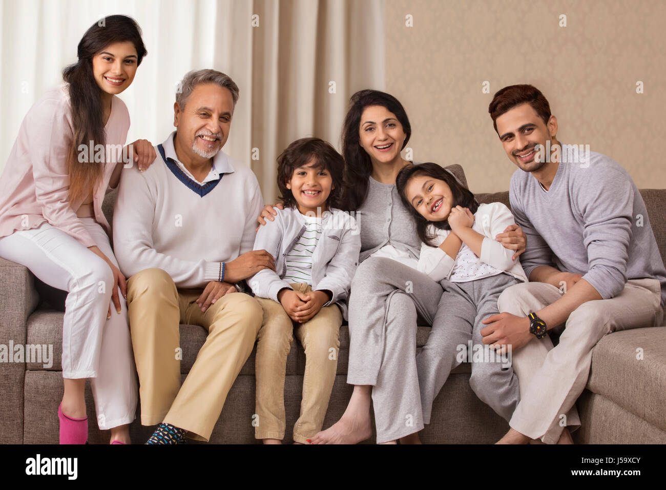 Happy multi-generation family sitting together on sofa Stock Photo - Alamy
