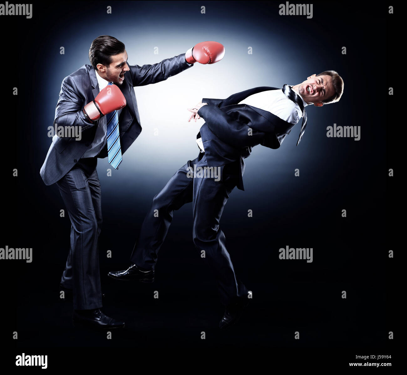Two young businessman boxing againts dark background Stock Photo - Alamy