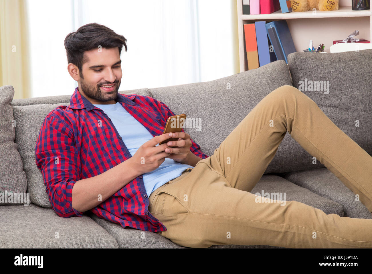 Man using cell phone on sofa Stock Photo - Alamy