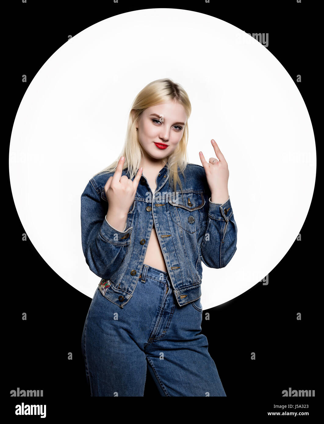 young hooligan in jeans and a denim jacket shows different signs with ...