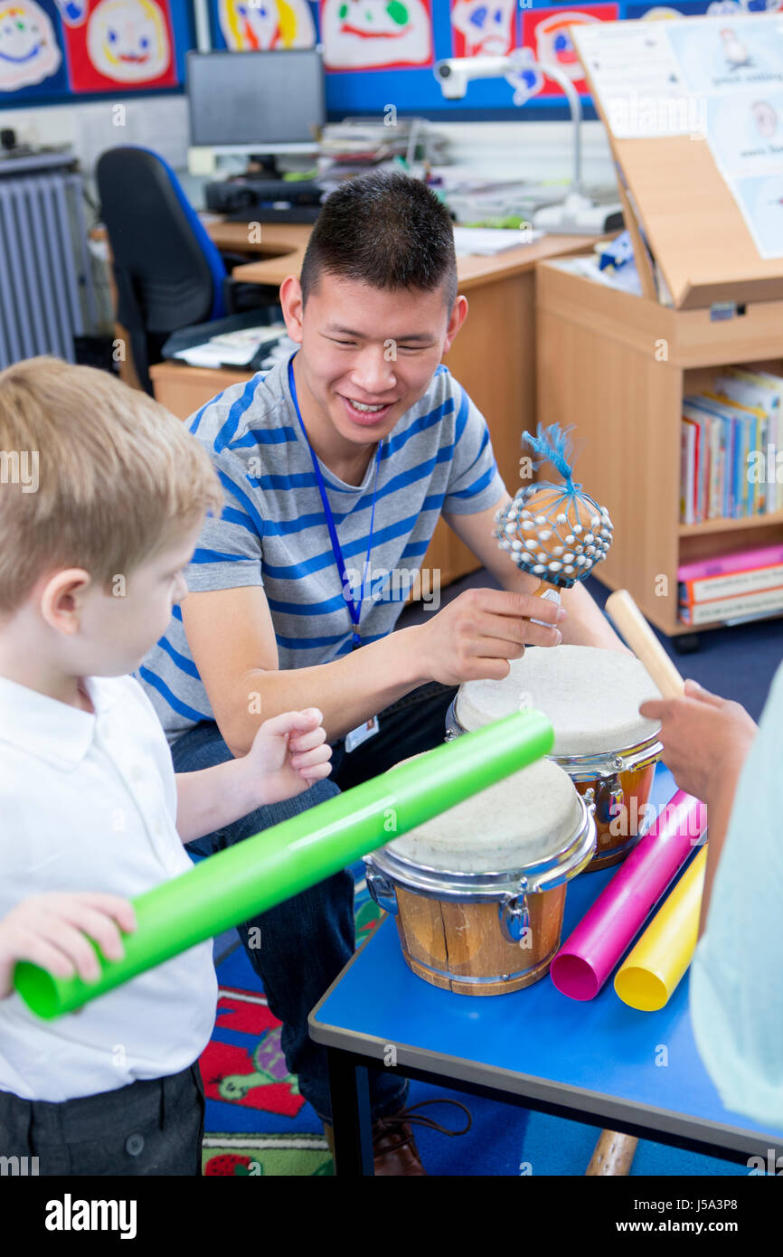 Nursery teacher playing with musical instruments with his student Stock ...