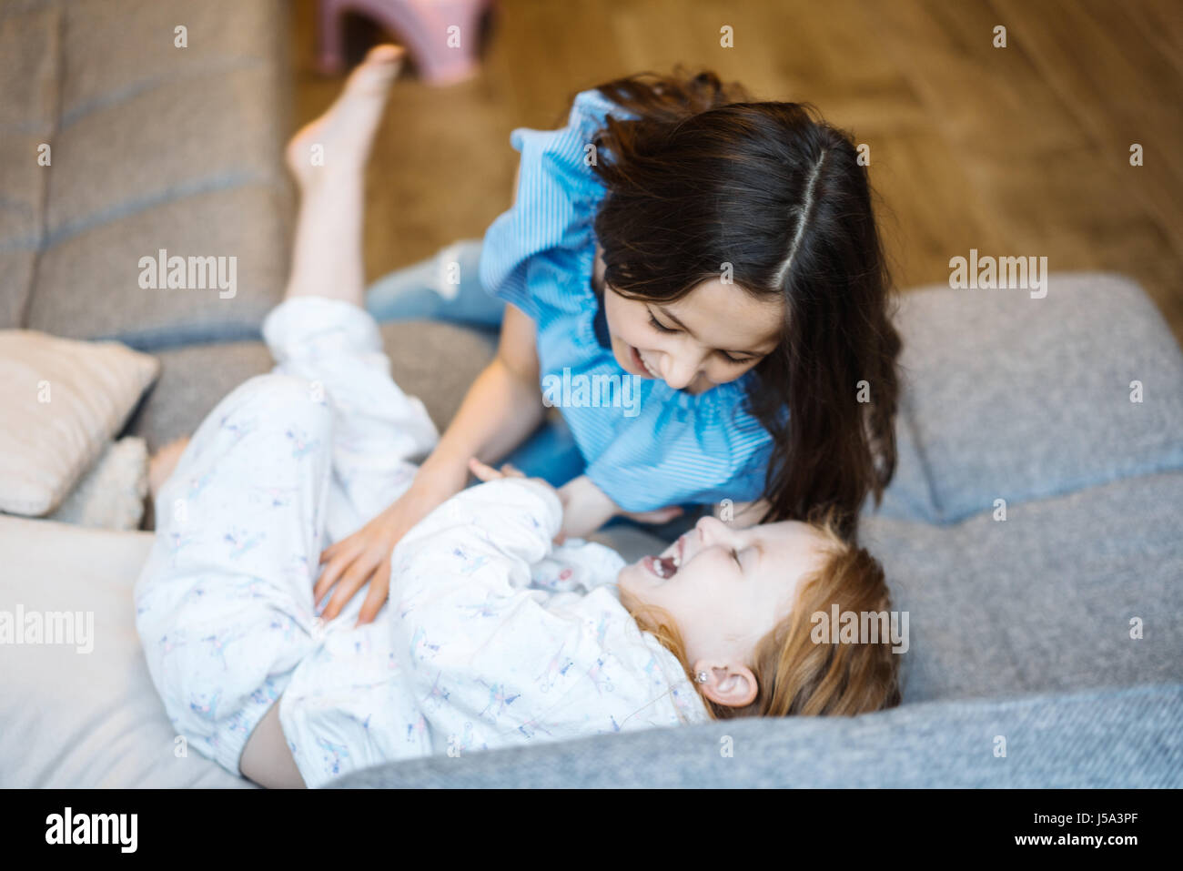 two sisters playing together on the big couch Stock Photo - Alamy